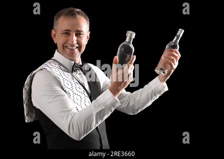 Mature waiter with bottles of vodka on black background Stock Photo - Alamy