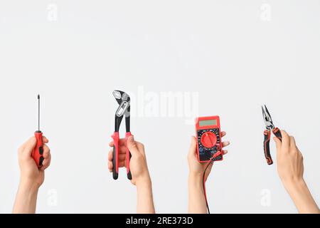 Electrician hands with tools on grey background Stock Photo - Alamy