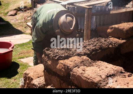 Man building with his hands an adobe house with adobe bricks and mud ...