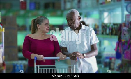 Diverse customers conversing inside grocery store with shopping cart ...