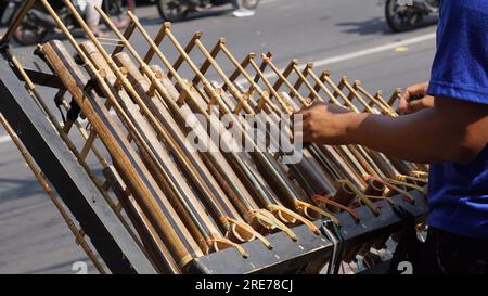 A man is playing angklung. That is a multitonal musical instrument that ...