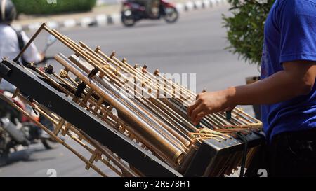 A man is playing angklung. That is a multitonal musical instrument that ...
