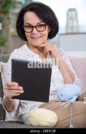 Smiley mature woman standing and using a laptop Stock Photo - Alamy