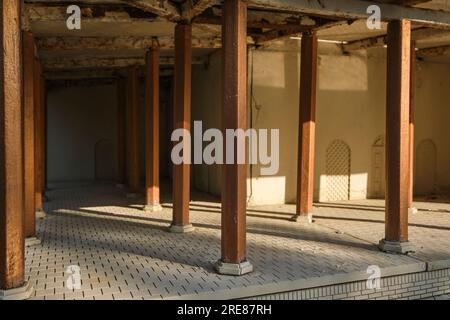 A view of an old mosque with a porch, portico of slender wood columns ...