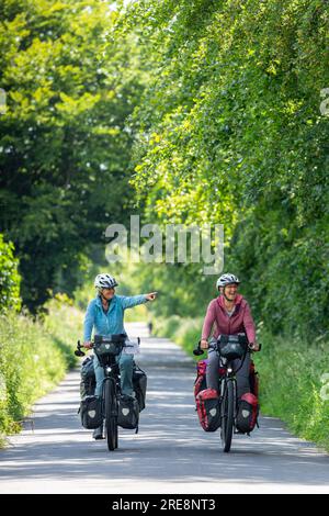 Two senior women cycle touring with full panniers Stock Photo - Alamy