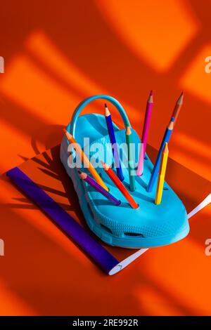 From above of plastic blue clog with holes placed on orange floor ...