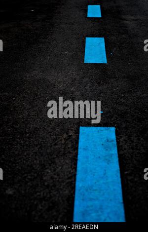 Dashed blue road marking line in perspective, centered in the frame ...