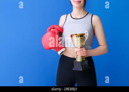 Female boxer with gold cup on black background Stock Photo - Alamy