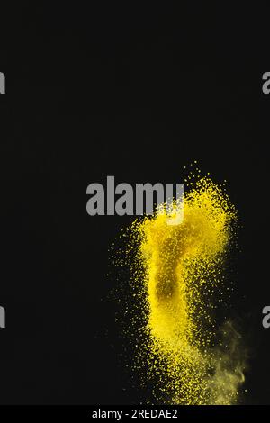 Close up of yellow sand thrown in the air and copy space on black ...