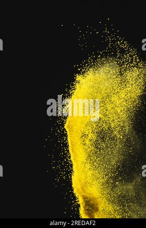 Close up of yellow sand thrown in the air and copy space on black ...