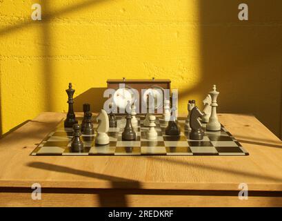 A secluded chess game set up on a table in a yellow room lit by a ...