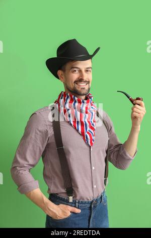 Handsome cowboy with smoking pipe on green background Stock Photo - Alamy