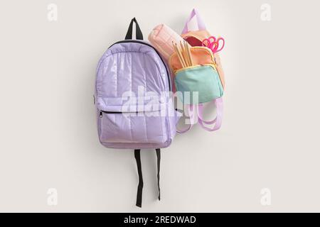 School backpacks and stationery on light blue background with space for ...
