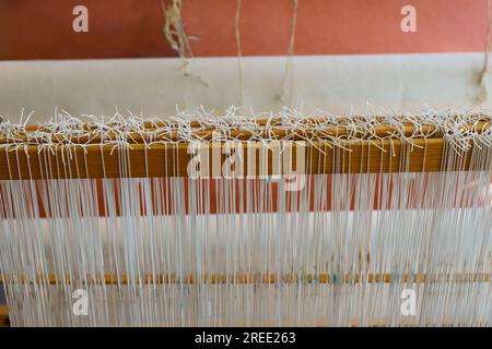 Close-up of a floor loom warp threads and heddles for textile weaving ...