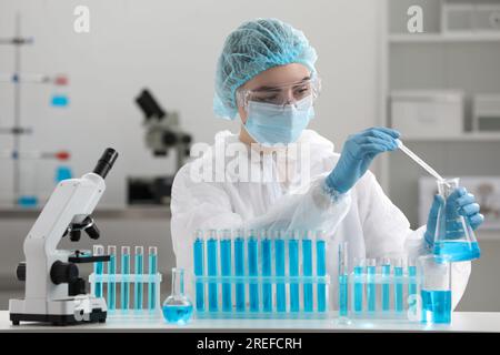 Scientist dripping sample into flask in laboratory. Medical research ...