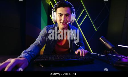 Happy young man gamer streamer in headphones playing on computer ...