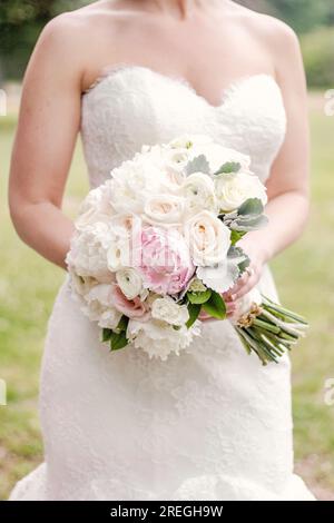 Bridal bouquet of white peony roses and wedding rings nearby. Wedding ...