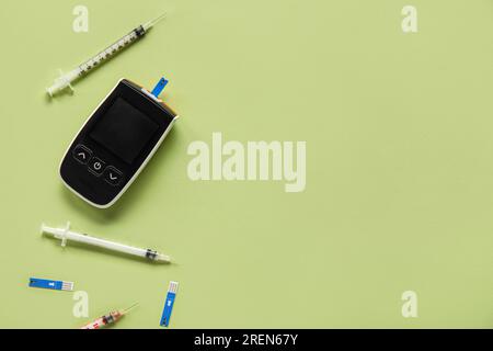 Glucometer with strips and syringes on green background. Diabetes ...