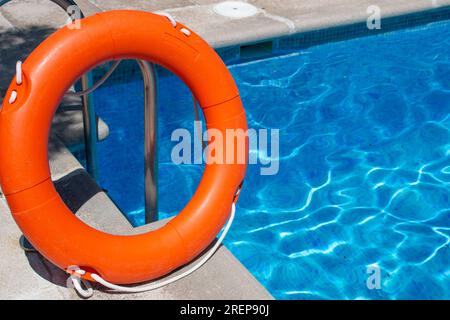 Orange rescue float resting on the steel ladder of a swimming pool ...