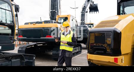 Fleet manager with a digital tablet stands next to electric trucks at ...