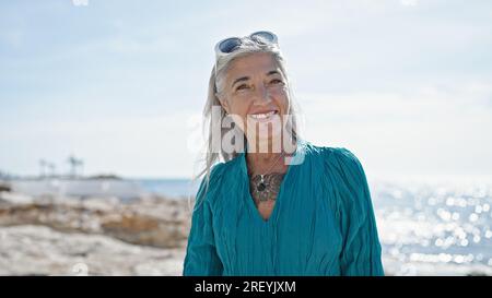 Middle age grey-haired woman doing yoga exercise sitting on table at ...