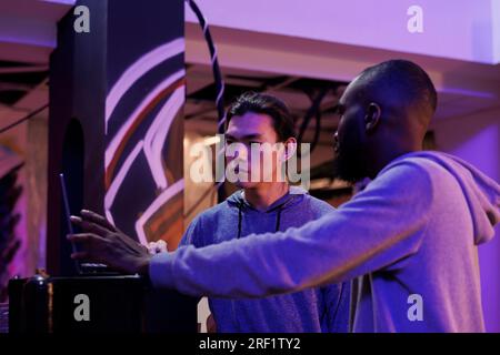 Hackers analyzing and discussing malicious code on computer screen, planning internet crime. Two ...