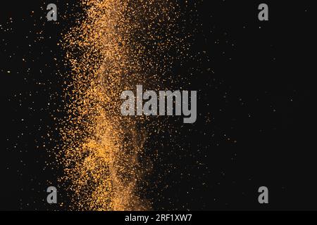 Close up of orange sand thrown in the air and copy space on black ...