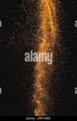 Close up of orange sand thrown in the air and copy space on black ...