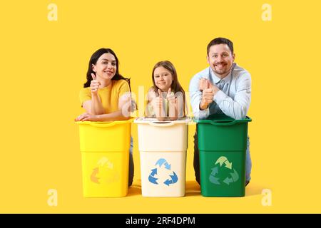 Family with recycle bins on yellow background Stock Photo - Alamy