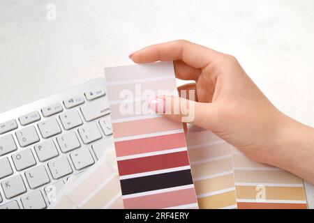 Hand with color palettes, PC keyboard, paint roller and notebook on ...