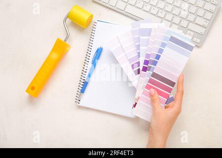 Color palettes, PC keyboard, paint roller and notebook on light ...