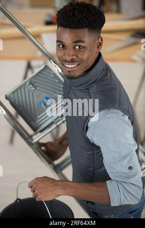 cheerful young man carrying ladder Stock Photo - Alamy