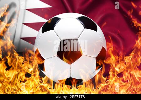 FOTOMONTAGE, Schwarz-weißer Fußball mit Flammen und Fahne von Katar ...