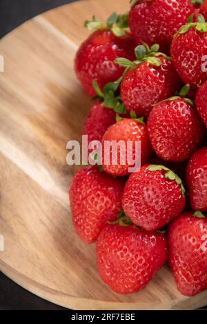 A ripe, juicy, red strawberry lying on a plate, among the green ...