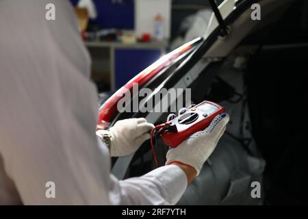 A man diagnoses a car battery with a tester, close-up. Battery repair ...