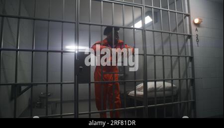 African American Inmate In Orange Uniform Crying Behind Prison Bars ...