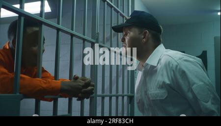 Warden brings guilty prisoner in jail cell and takes off handcuffs ...