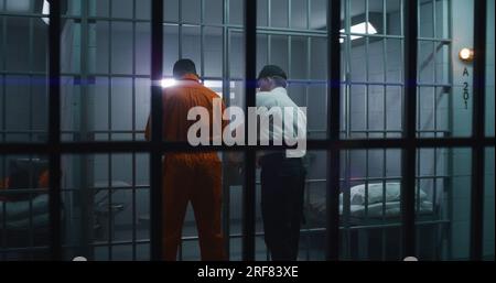 Warden brings guilty prisoner in jail cell and takes off handcuffs ...