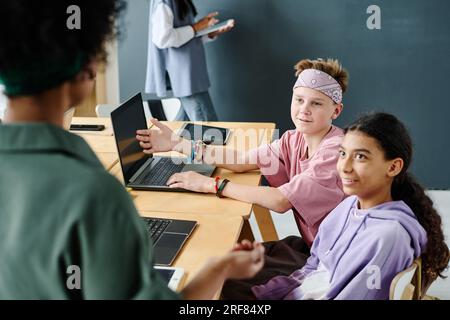 Group of children discussing new software together on computer while ...