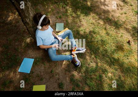 Hispanic school boy wearing headphones, preparing homework while ...