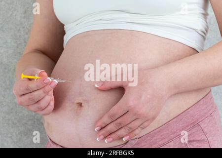 Blood thinners concept. Pregnant woman making injection in stomach ...