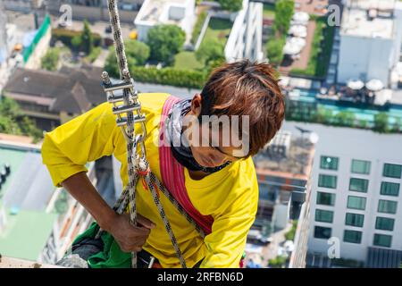 Thai maintenance worker abseiling outside high rise building, Sukhumvit ...