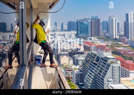 Thai maintenance worker abseiling outside high rise building, Sukhumvit ...