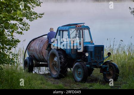 Agricultural farm wheeled tractor draws water into tank to dissolve ...