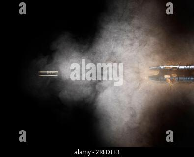 Copper colored bullet just leaving the gun with smoke and sparks flying ...