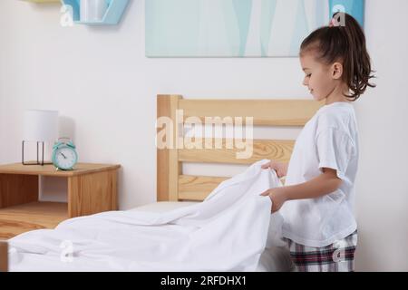 Cute girl changing bed linens in children room Stock Photo - Alamy