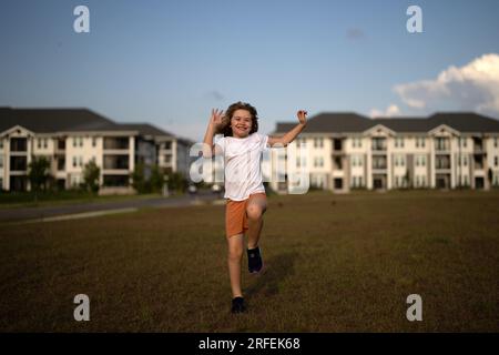 Cute kid boy running across american neighborhood street. Summer ...