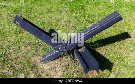 anti tank metal fortifications and hedgehogs on green grass, pieces of ...