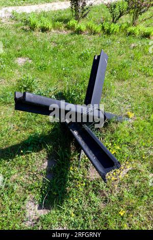 anti tank metal fortifications and hedgehogs on green grass, pieces of ...