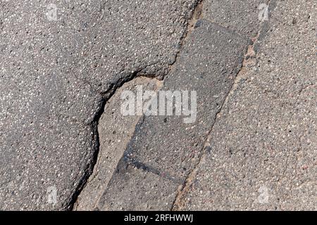 an asphalt road with a lot of holes and damage, a poorly made ...
